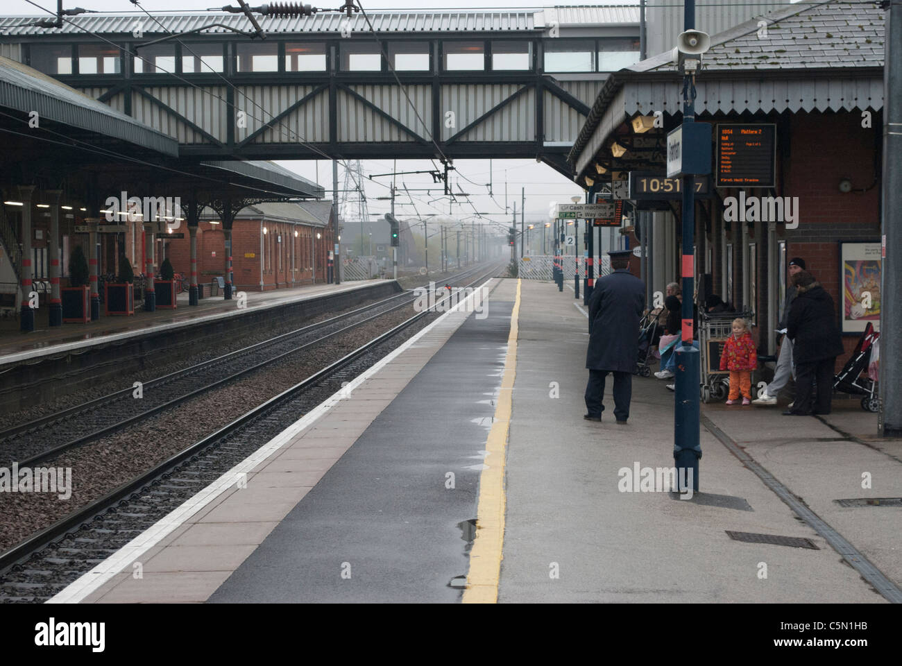 Platform of Grantham station on dull wet day with guard and passengers ...