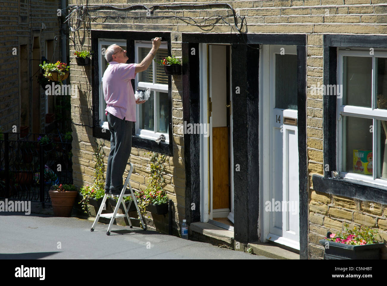 Elderly man painting the window frames on his house, Luddenden ...