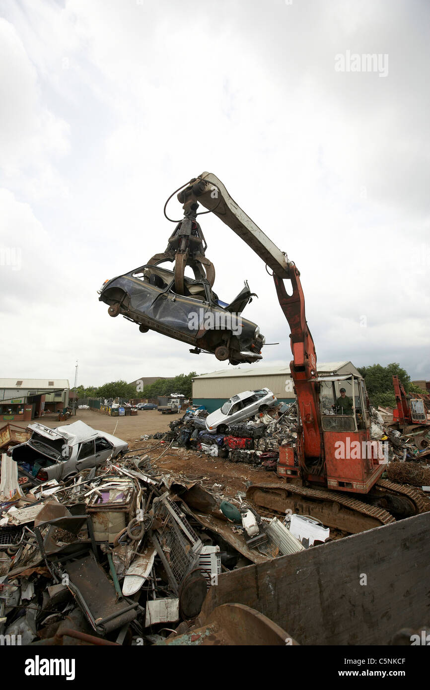 Crane fitted with grabbers lifting scrap car for recycling in a ...