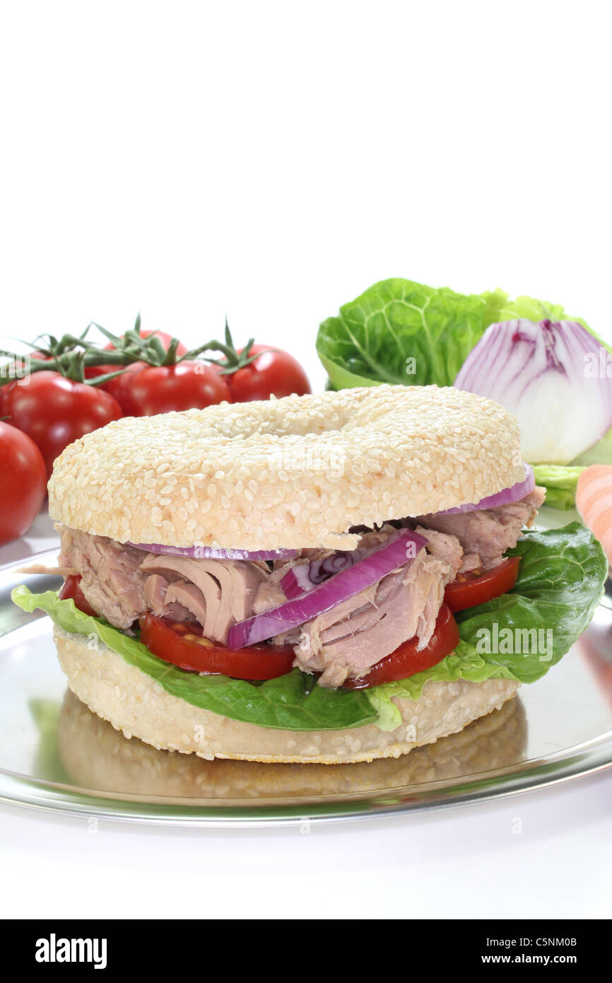 Bagel with tuna, tomatoes, onions, and lettuce on white background ...