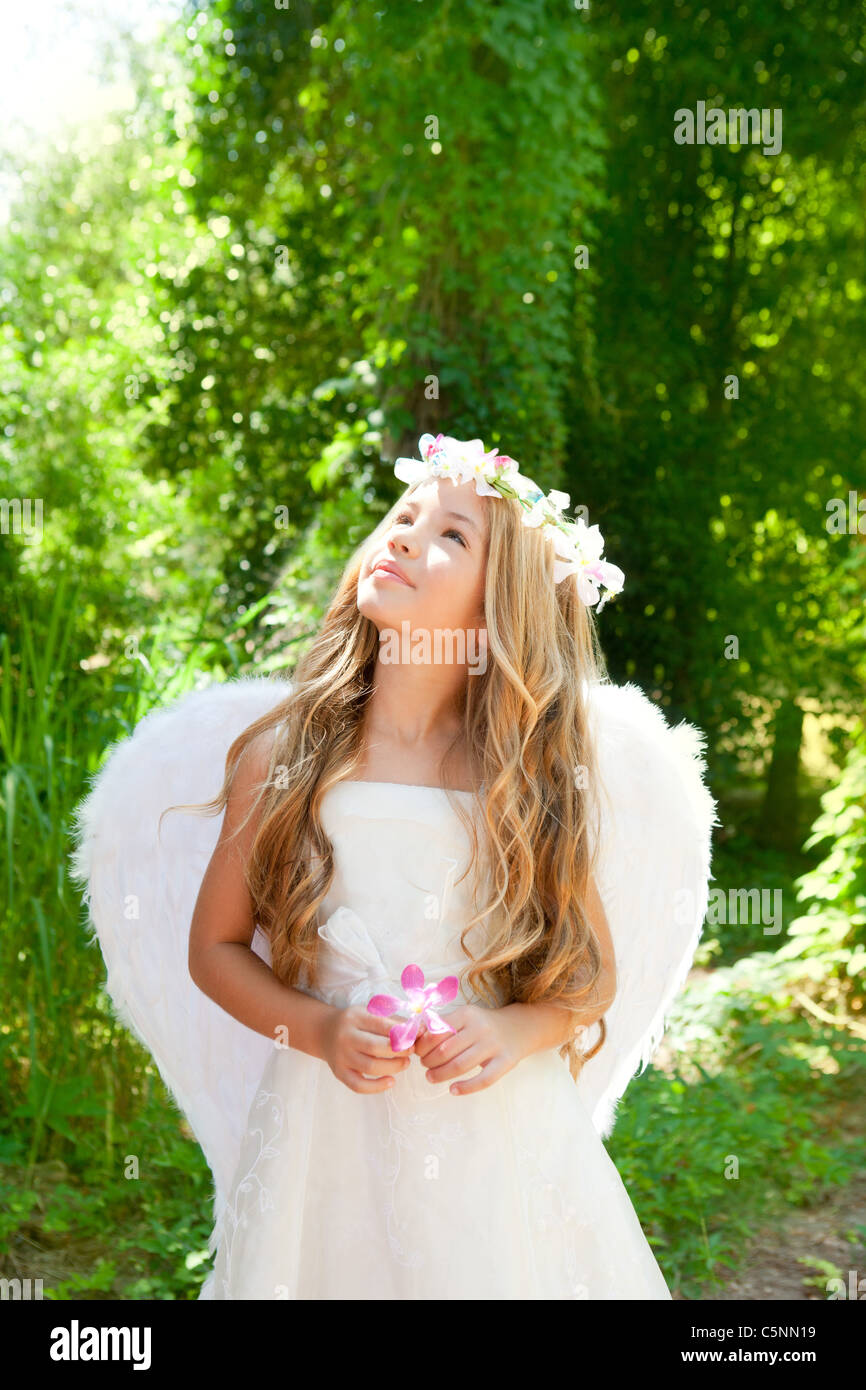 Angel children girl in forest holds flower in hand looking sky with ...