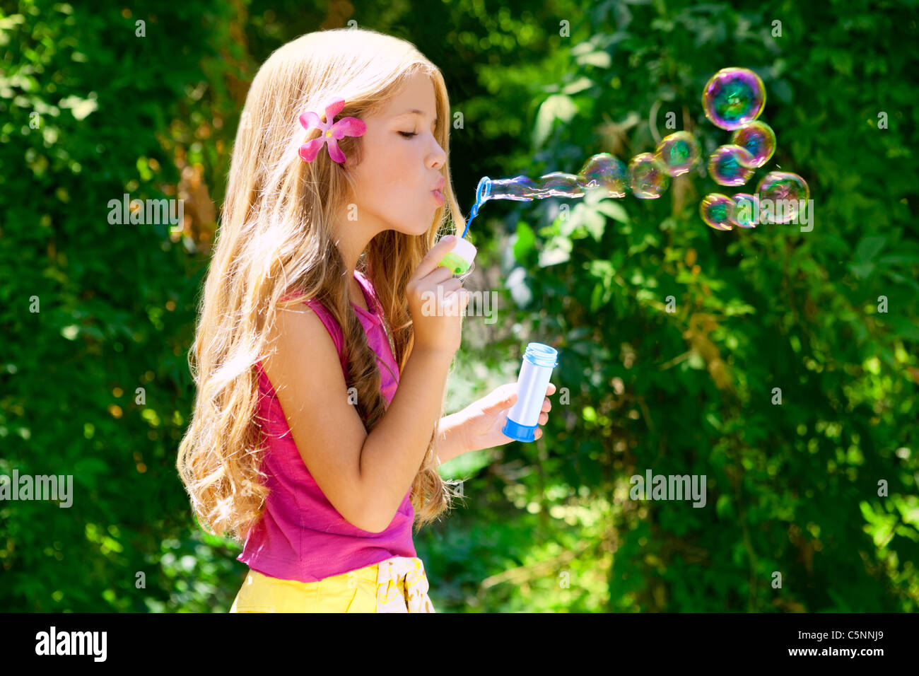 Children blowing soap bubbles in outdoor forest with fashion pink ...