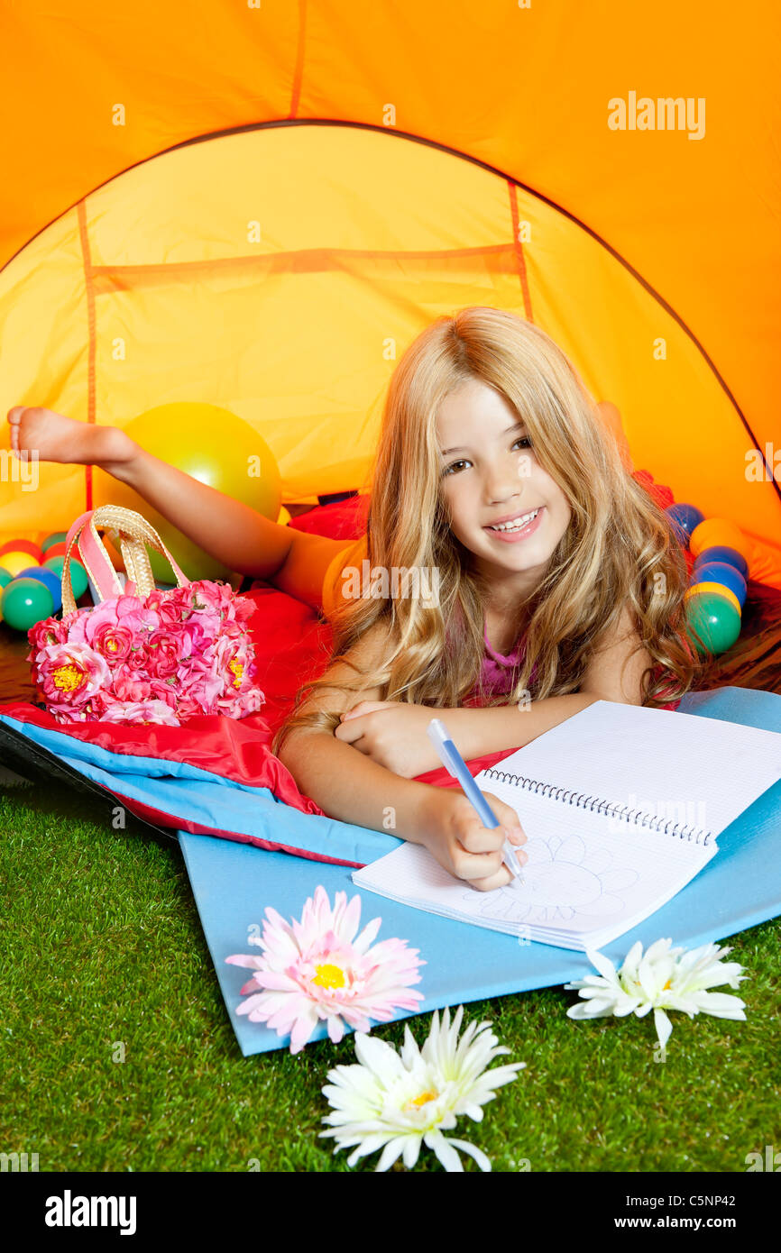 Children girl writing a notebook in camping tent with flowers and grass ...