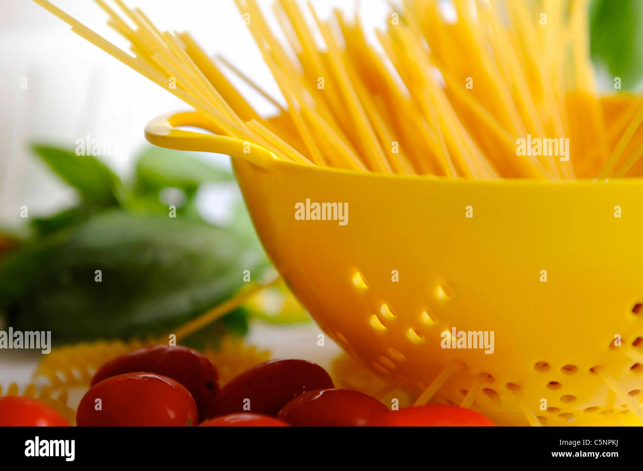 Raw spaghetti in a yellow colander Stock Photo - Alamy