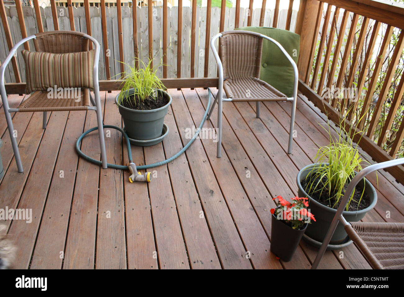 Outdoor Deck with potted plants, garden hose and chairs Stock Photo - Alamy
