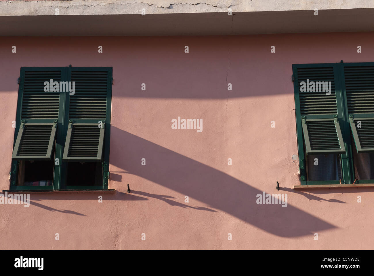 Green window shutters half open at the bottom cast long shadows across ...