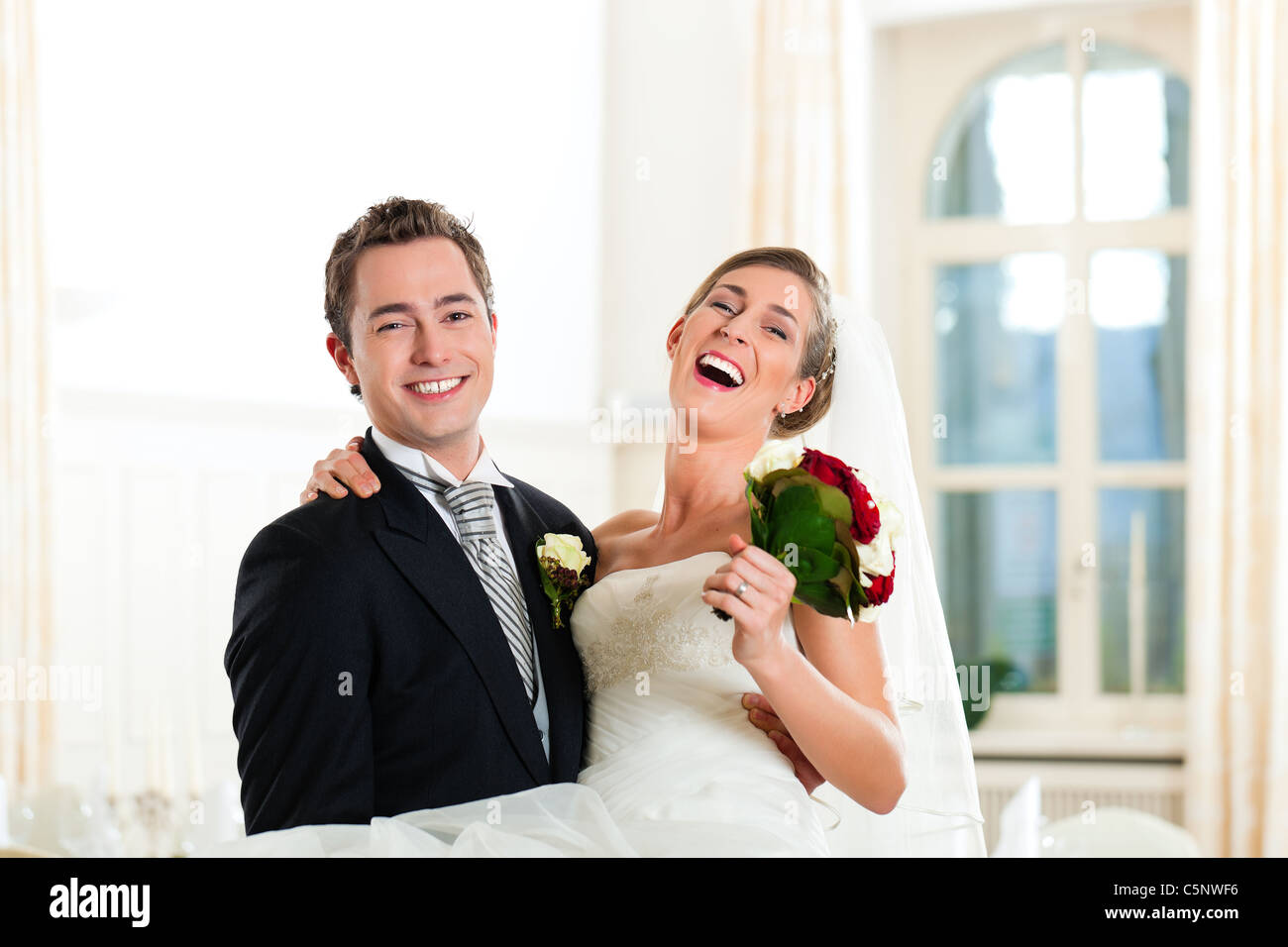 Bridal couple - groom is carrying his bride Stock Photo - Alamy
