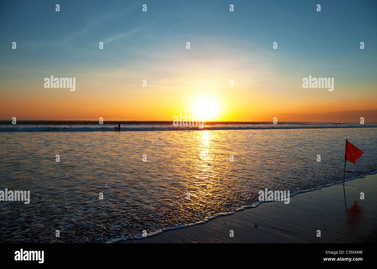 Red flag on Kuta beach in Bali at sunset Stock Photo - Alamy