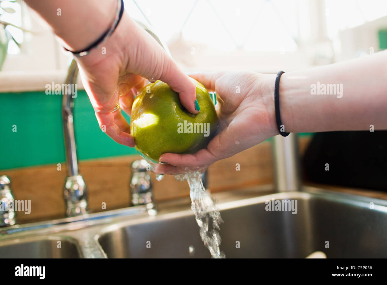 Teenage girl washing apple in kitchen sink Stock Photo - Alamy