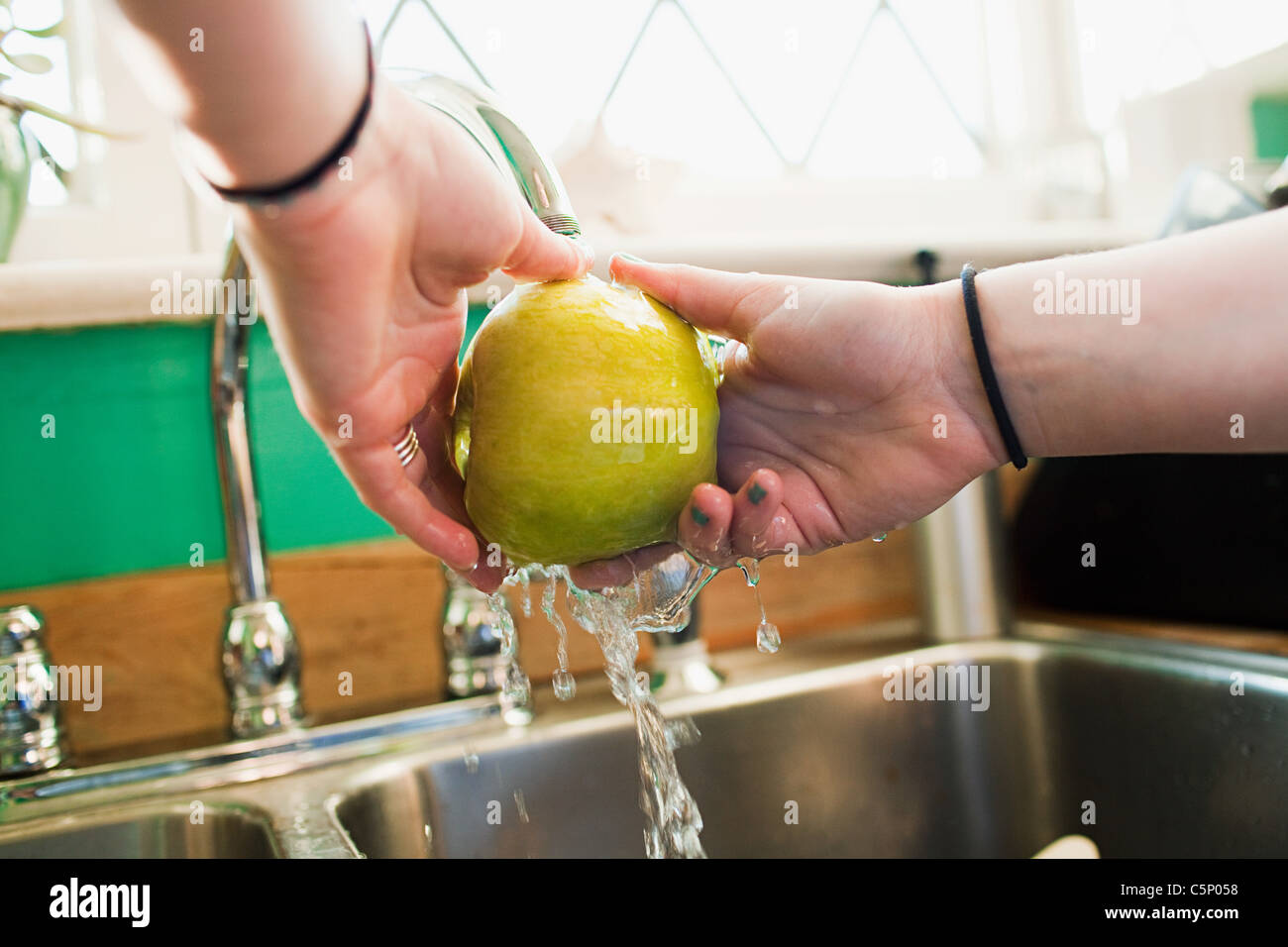 Teenage girl washing apple in kitchen sink Stock Photo - Alamy