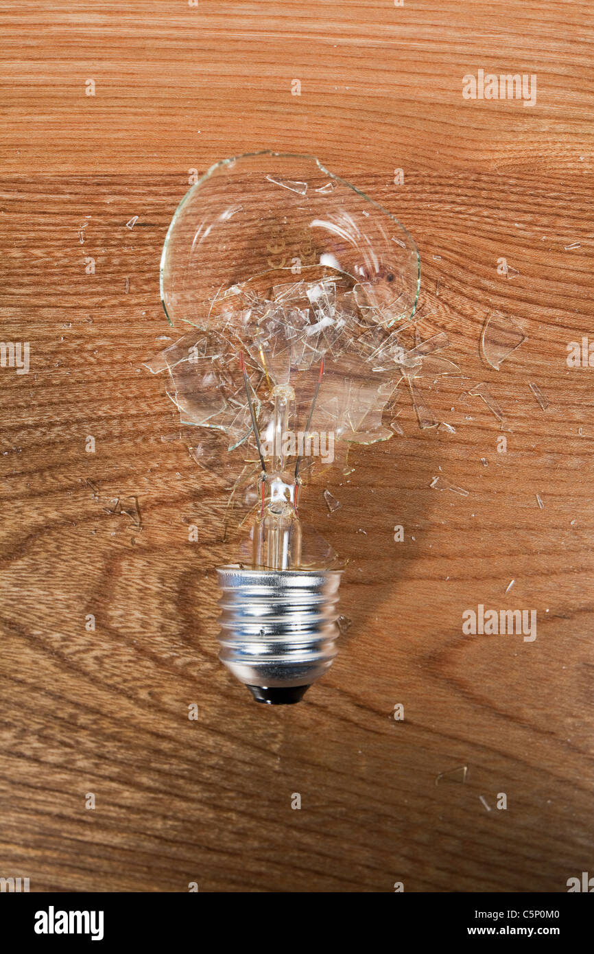 Smashed lightbulb against wooden background Stock Photo - Alamy