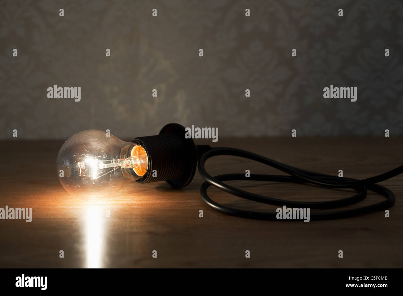 Illuminated lightbulb on table Stock Photo - Alamy