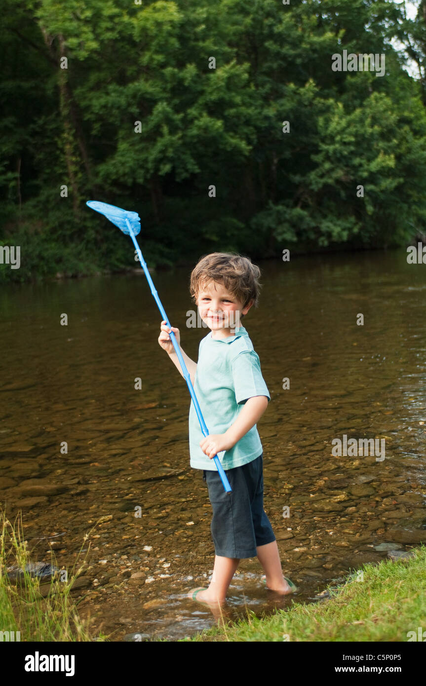 Boy holding fishing net by river Stock Photo - Alamy