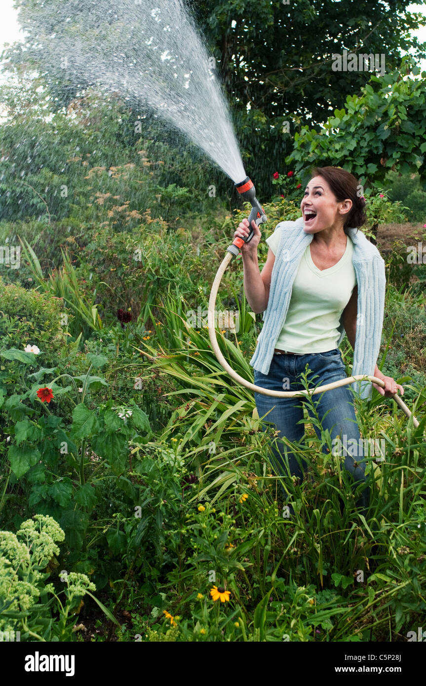 Woman spraying garden with hosepipe Stock Photo - Alamy