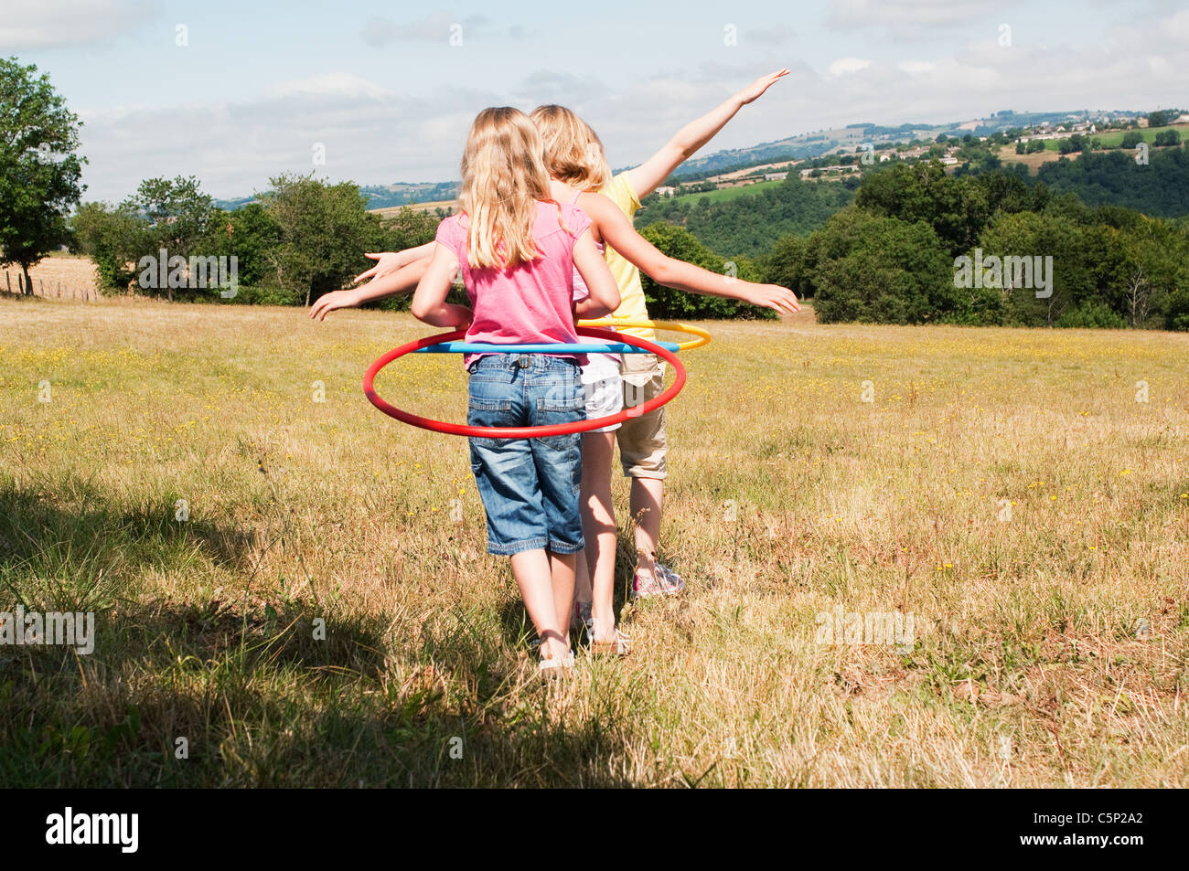 Three girls walking in field with plastic hoops Stock Photo - Alamy