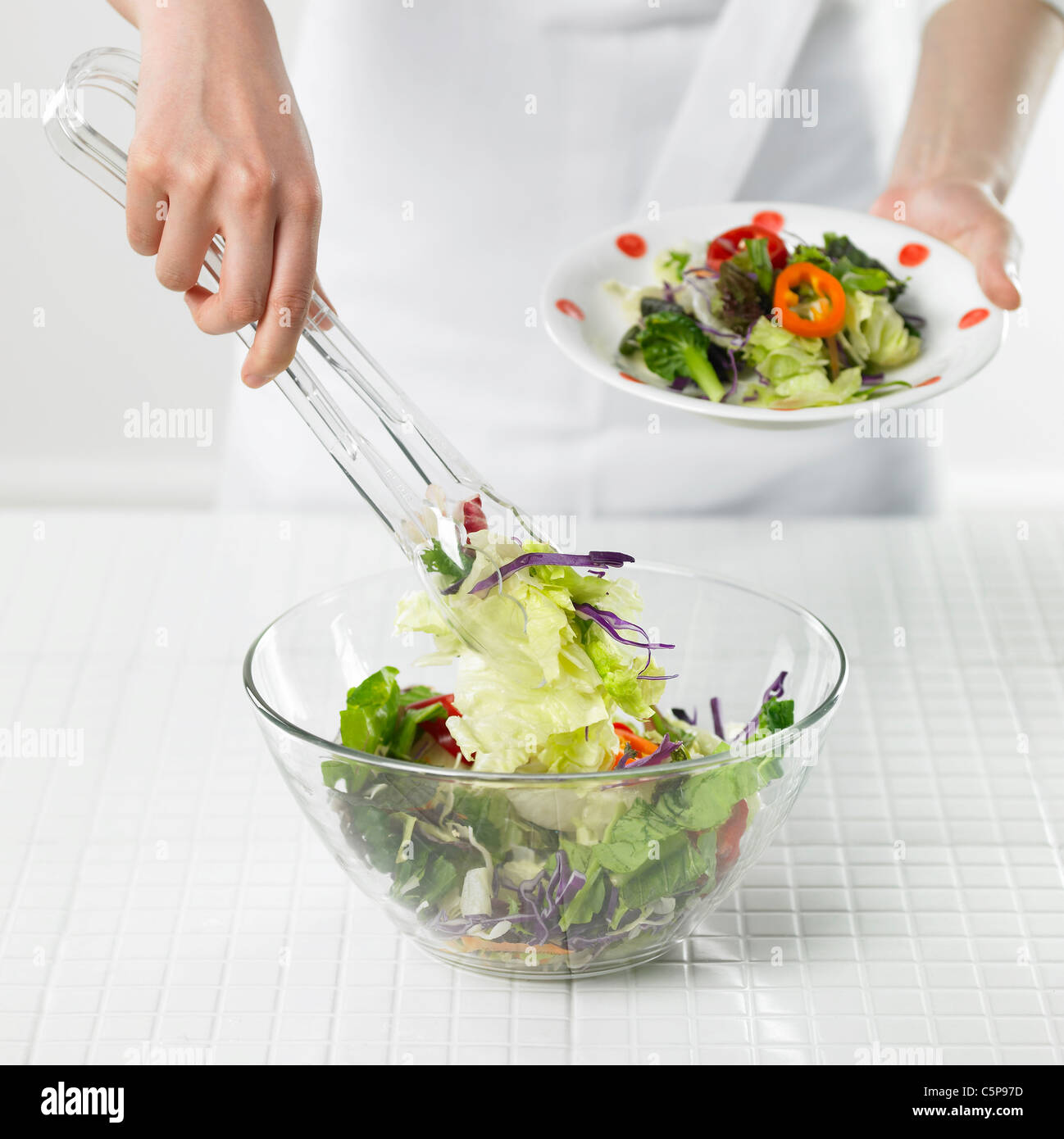 A person serving salad to a dish Stock Photo - Alamy