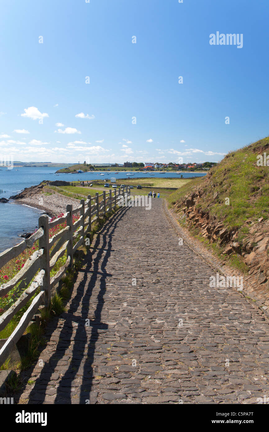 Path up to Lindisfarne Castle looking back to village and harbour Stock ...