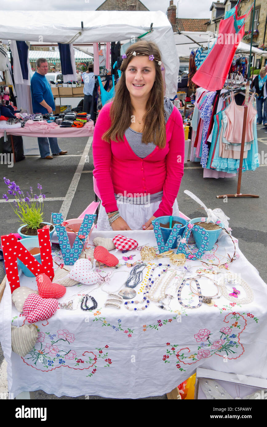 A young woman selling jewellery on a stall at the weekly Friday Market ...