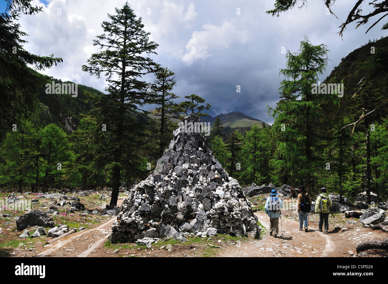 Hikers walking by a Tibetan Mani stone pile. Sichuan, China Stock Photo ...