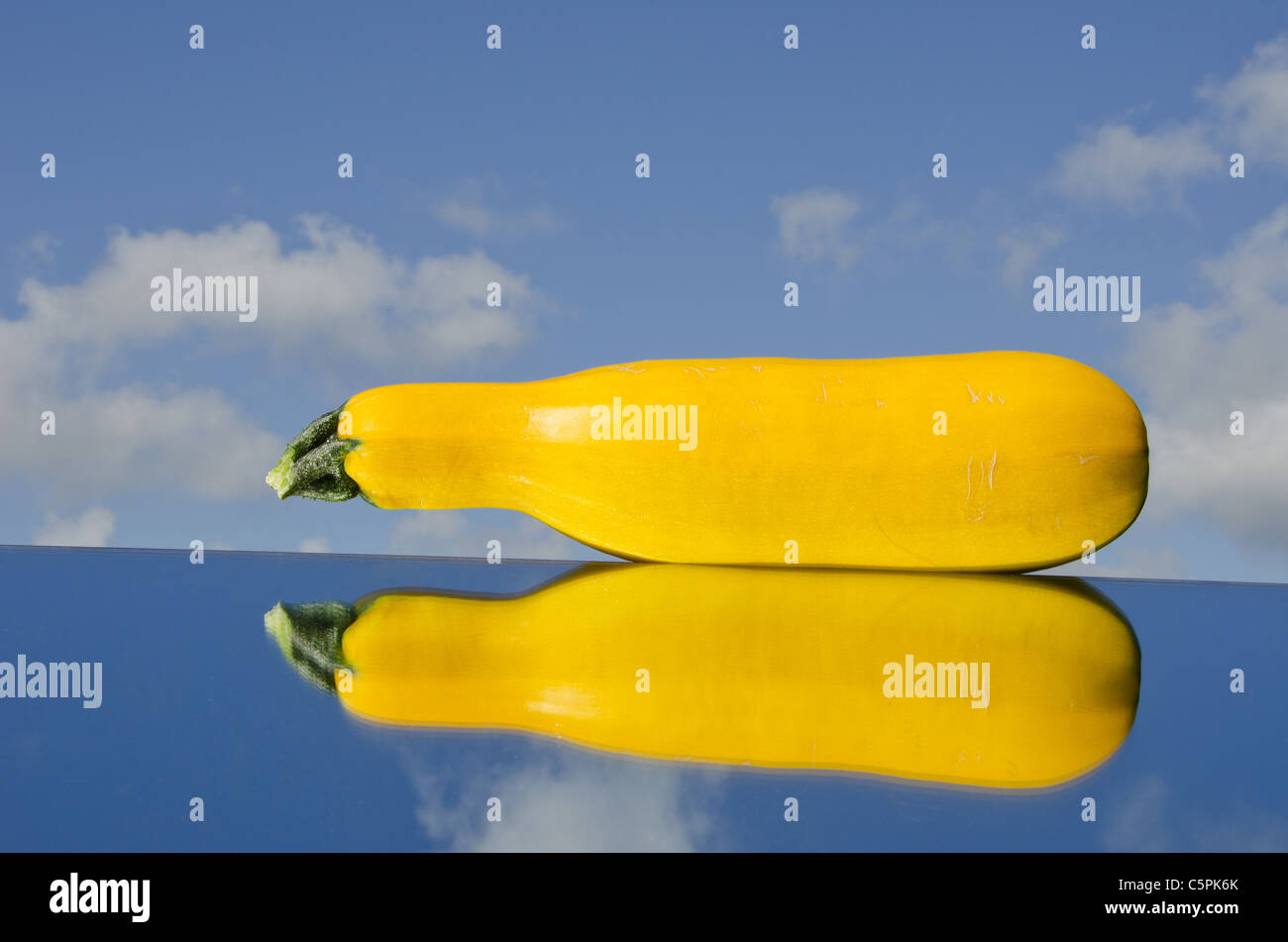yellow courgette on mirror and blue sky Stock Photo - Alamy