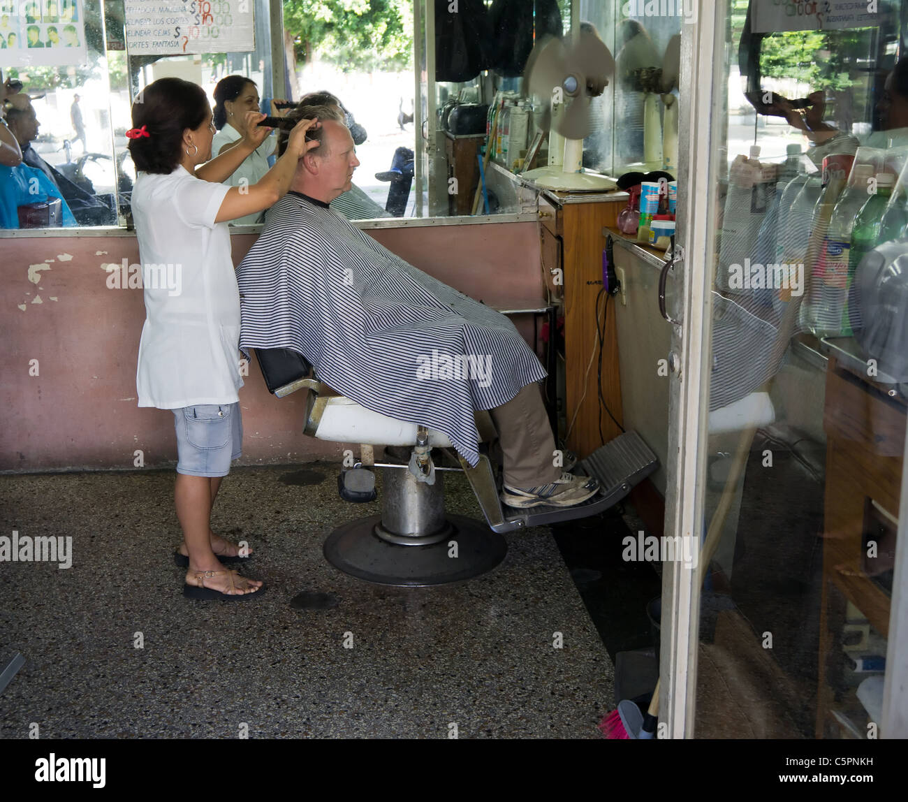 Man getting a haircut from a barber in Havana, Cuba Stock Photo - Alamy