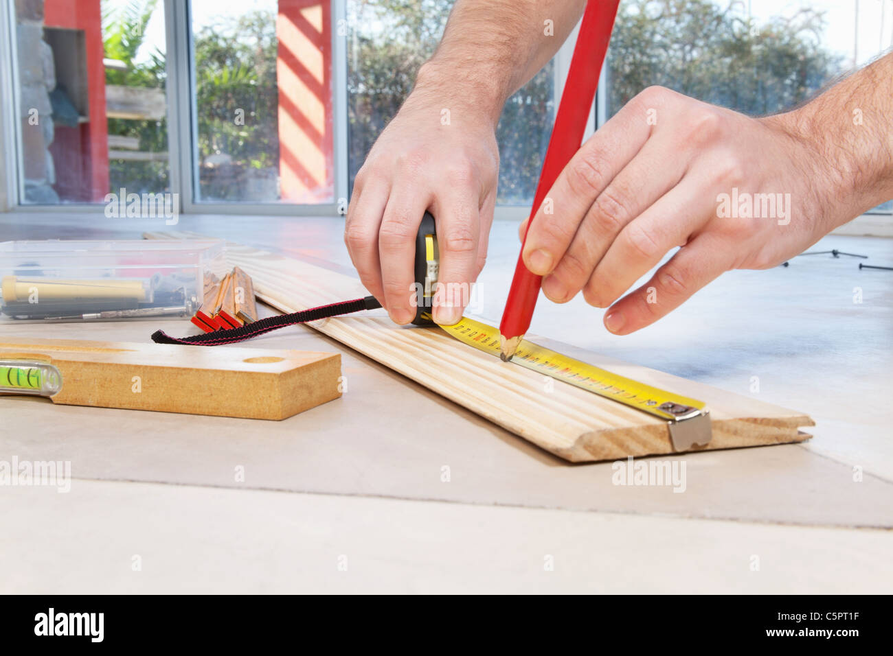 Close-up of engineer's hand marking on plywood with pencil and ...