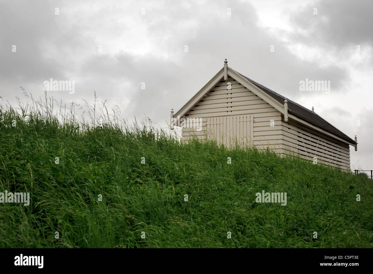 White boathouse on top of a green dike with cloudy weather Stock Photo ...