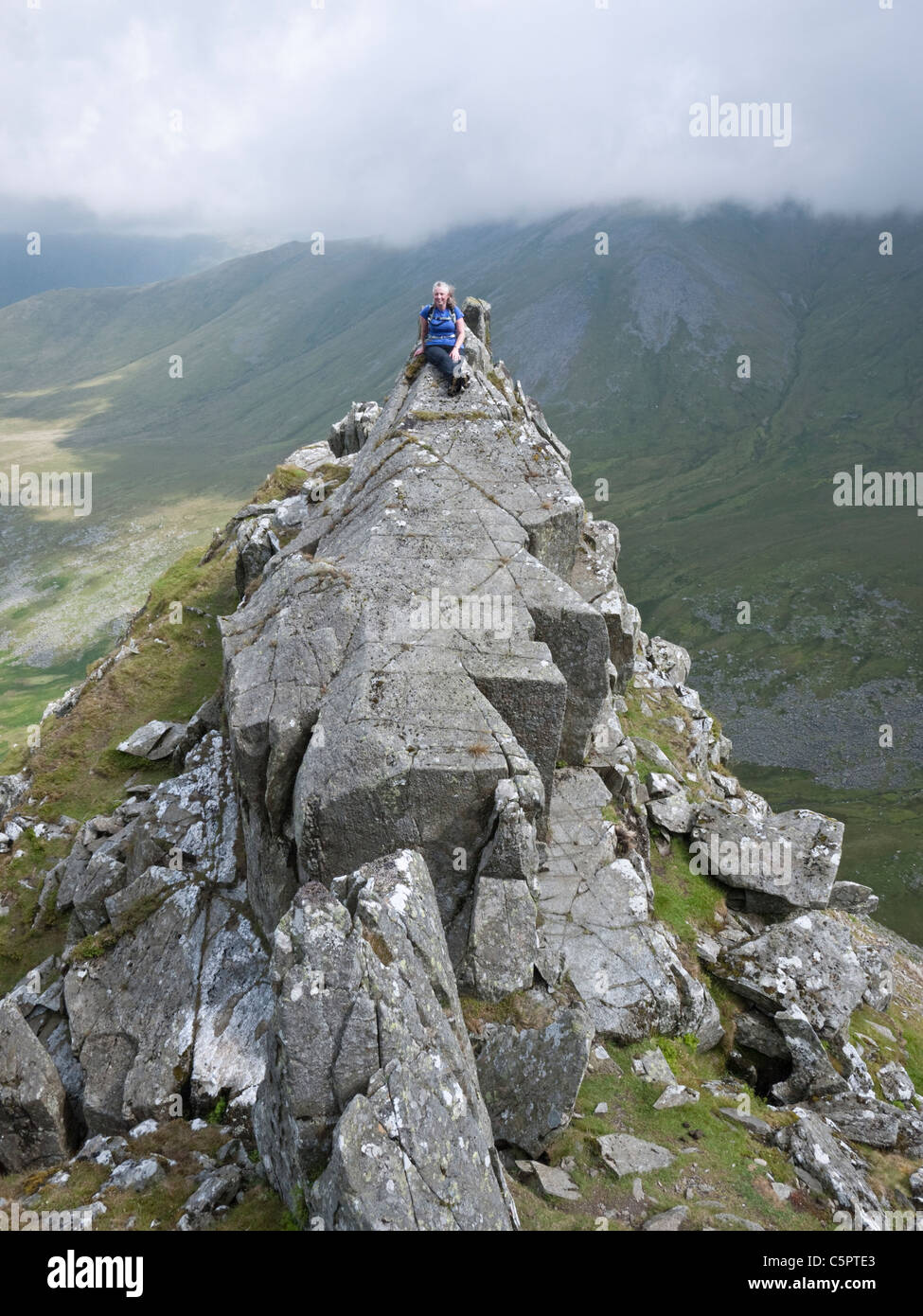 A female hill walker scrambling on the Crib Lem spur of Carnedd Dafydd ...