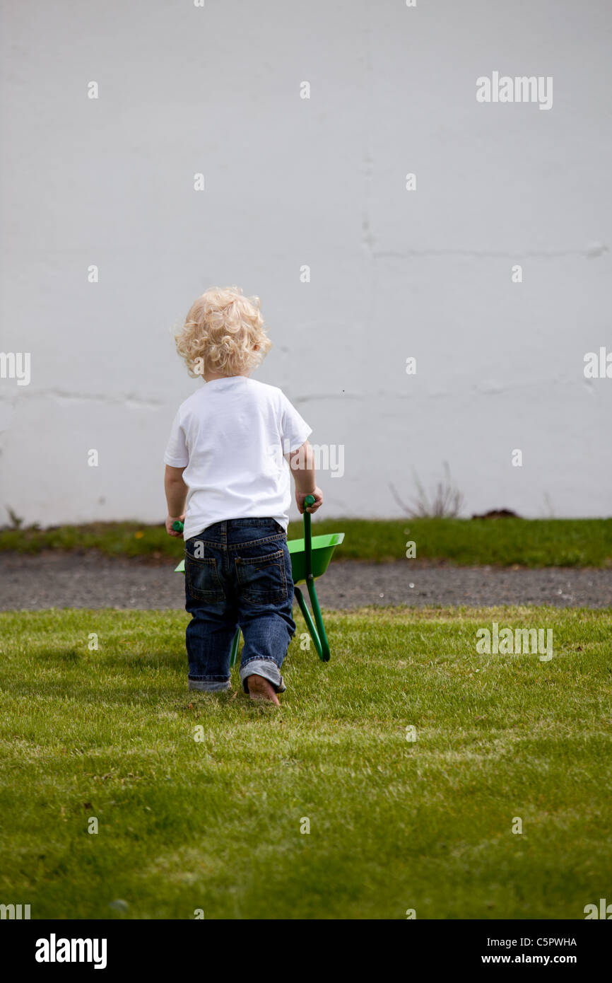 A young boy pushing a wheelbarrow on grass Stock Photo - Alamy