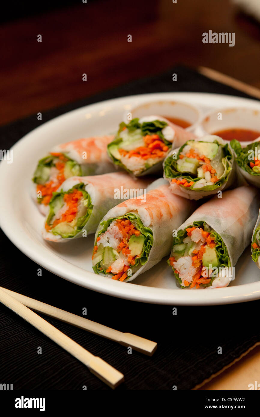 Angled view of a plate of spring rolls with sweet chili sauce; styled ...