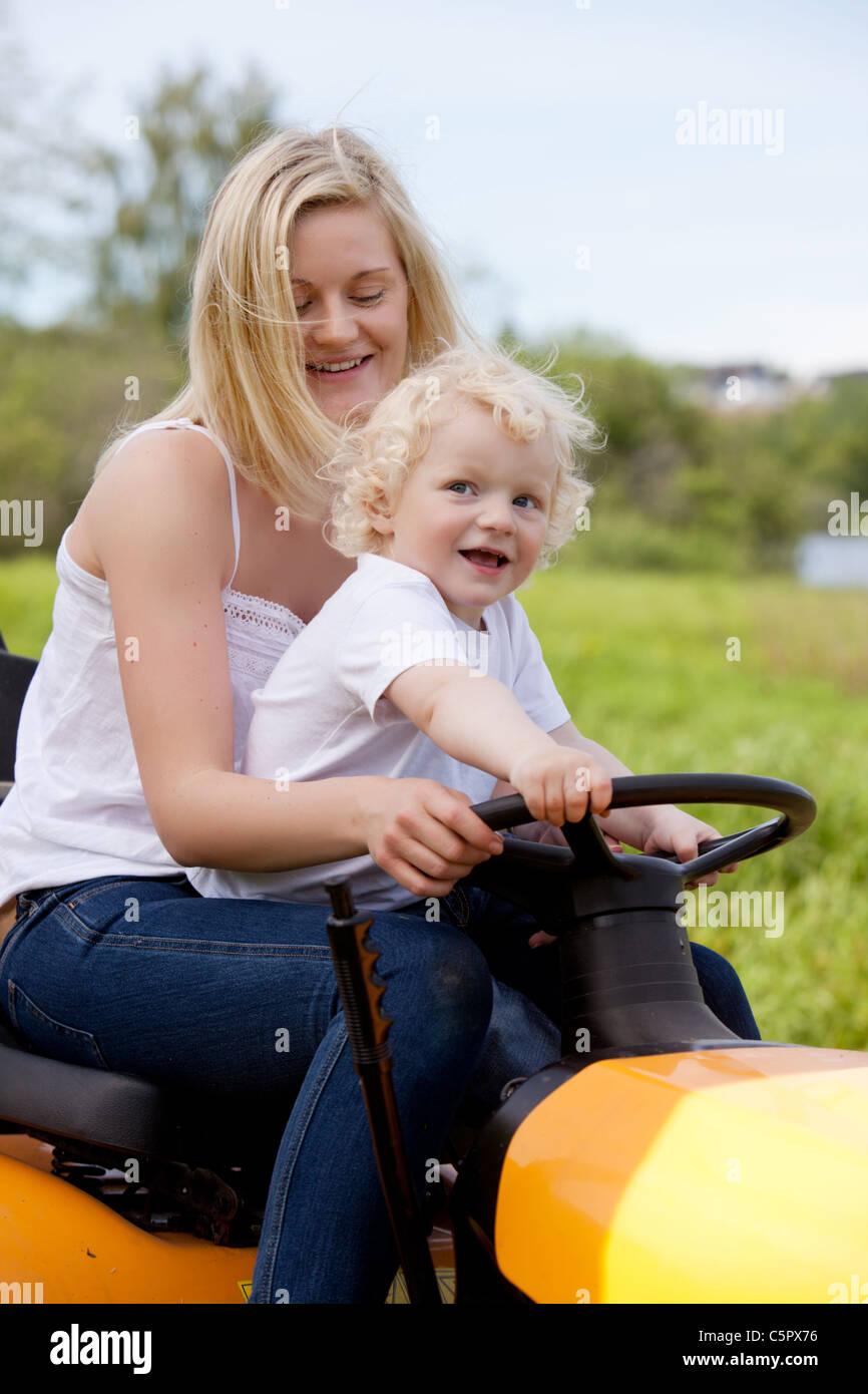 A mother driving a lawn mower tractor with happy smiling son Stock ...
