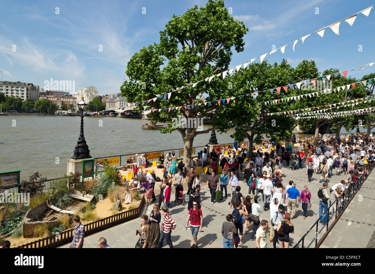 People walking alongside the river Thames on a sunny day in summer ...