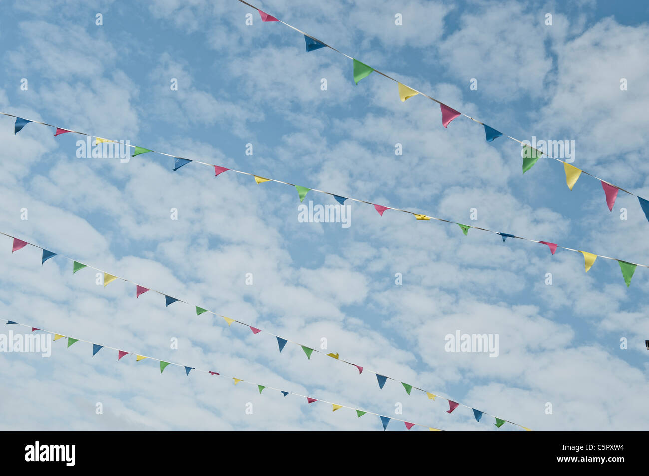 Strips of colourful bunting line diagonally across a sky slightly ...