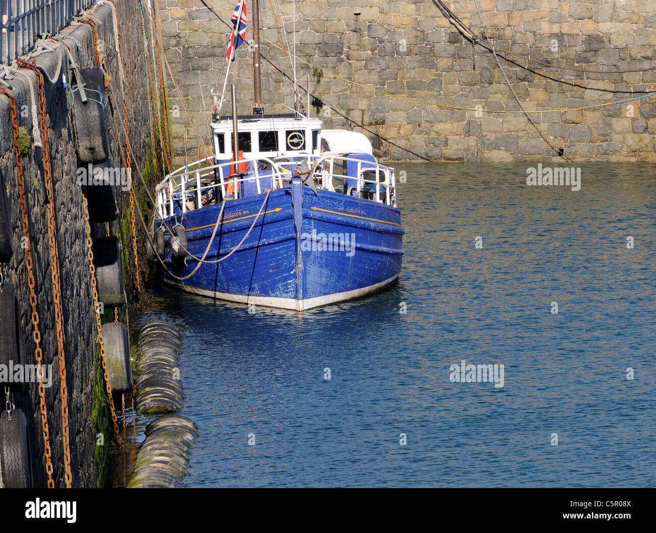 A blue fishing boat moored on the quay in the harbour. St Peter Port ...