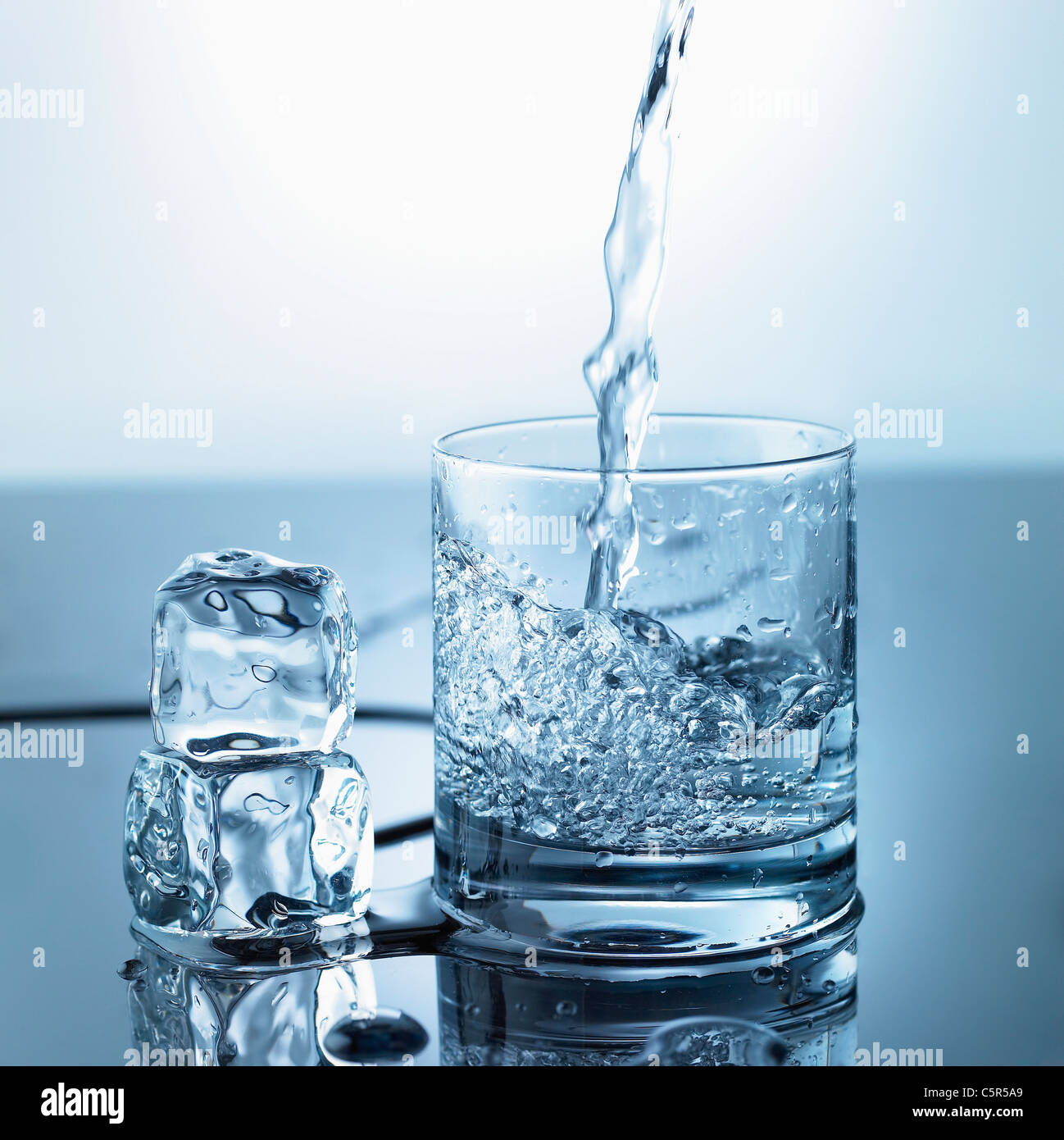 Water pouring down to the glass cup and ice cubes Stock Photo - Alamy