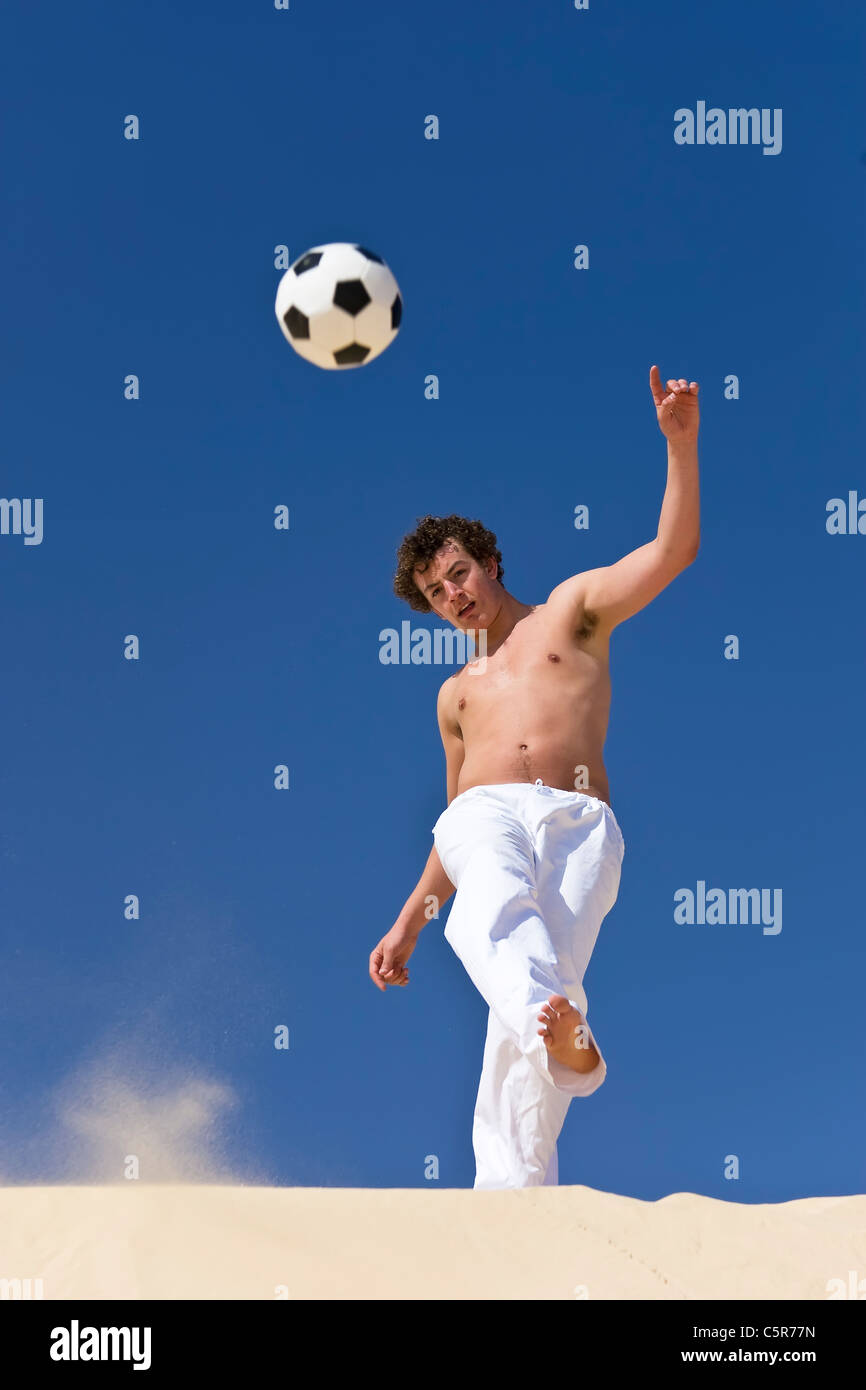 Beach soccer player passing ball Stock Photo - Alamy