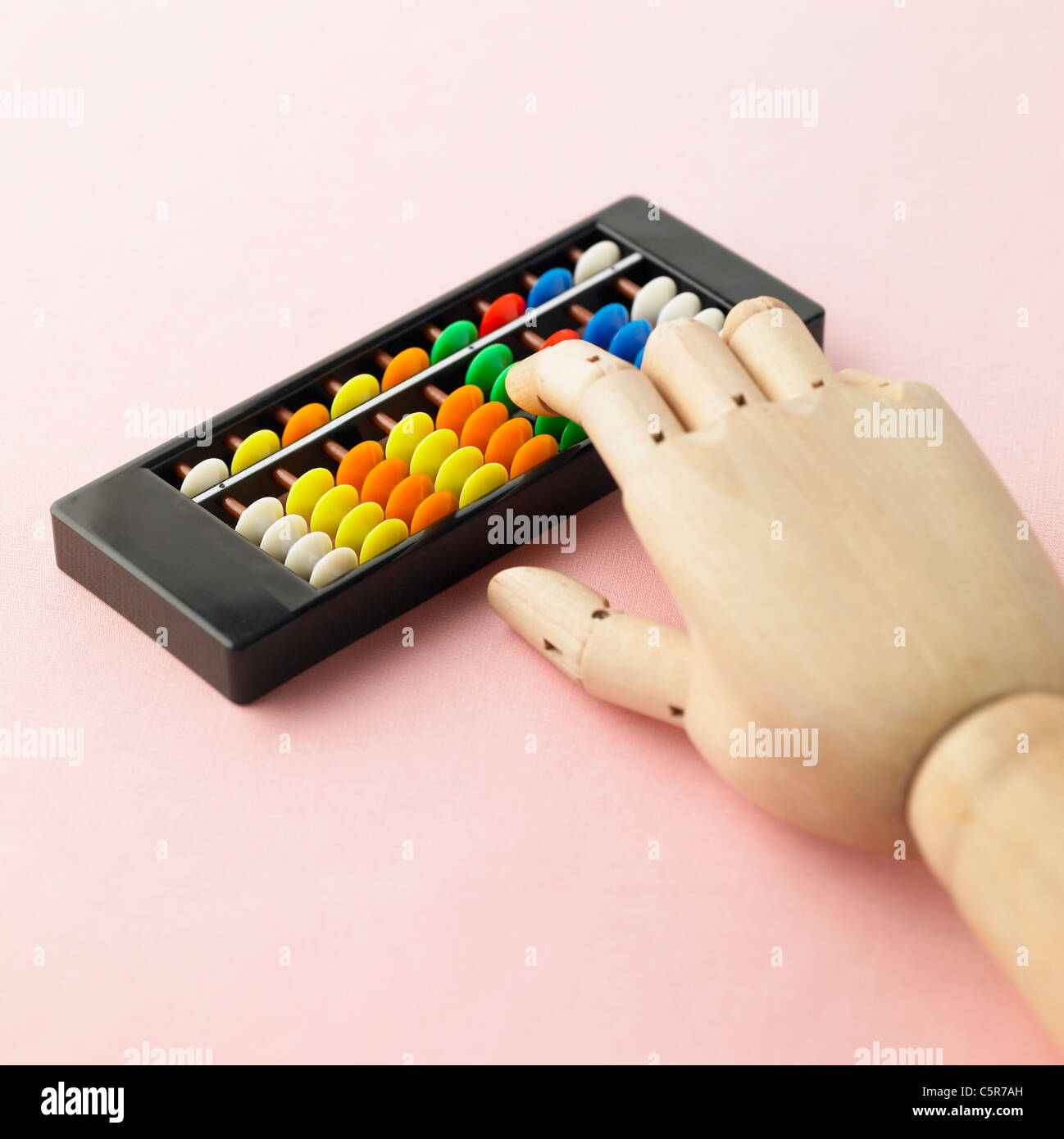 A wooden hand touching an abacus Stock Photo - Alamy