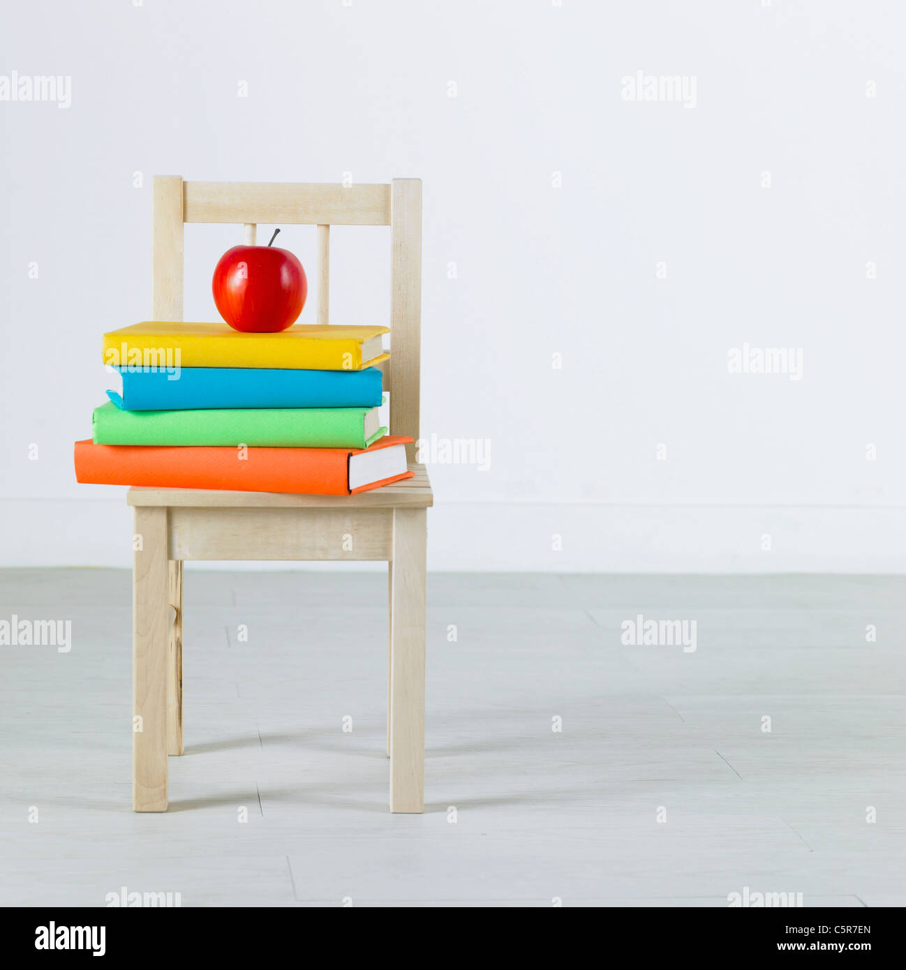 Books and an apple on a chair Stock Photo - Alamy