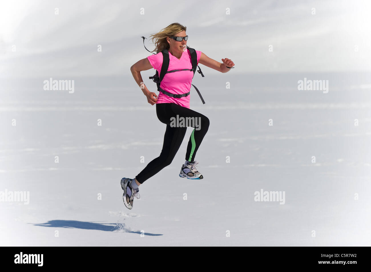 Woman jogging across snow covered frozen field Stock Photo - Alamy