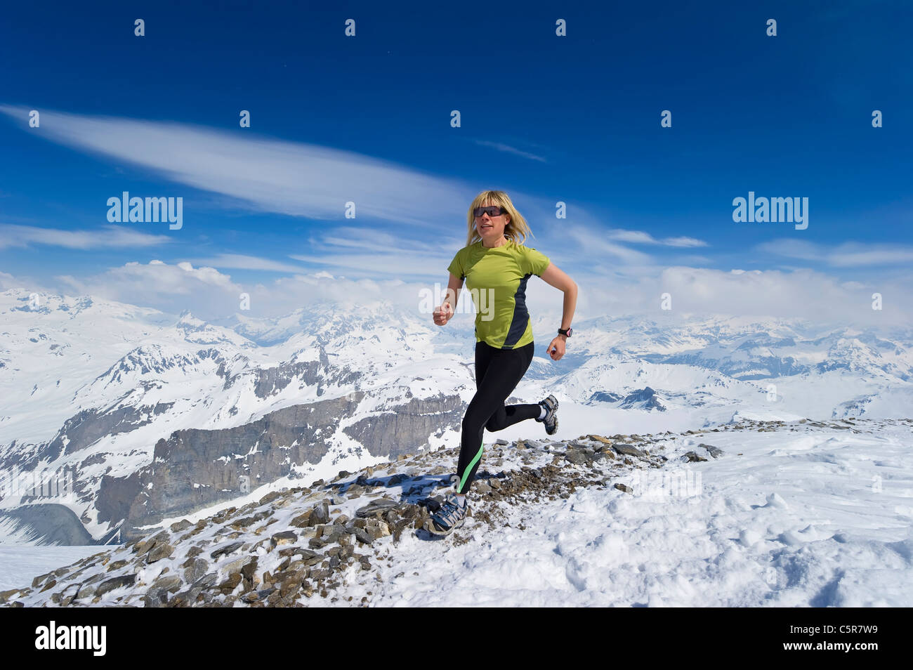 Woman jogging across snowy mountains Stock Photo - Alamy