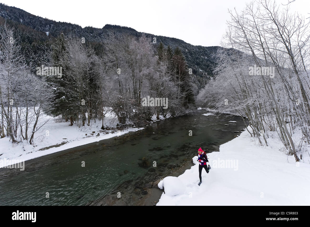 A jogger running alongside a snowy river Stock Photo - Alamy