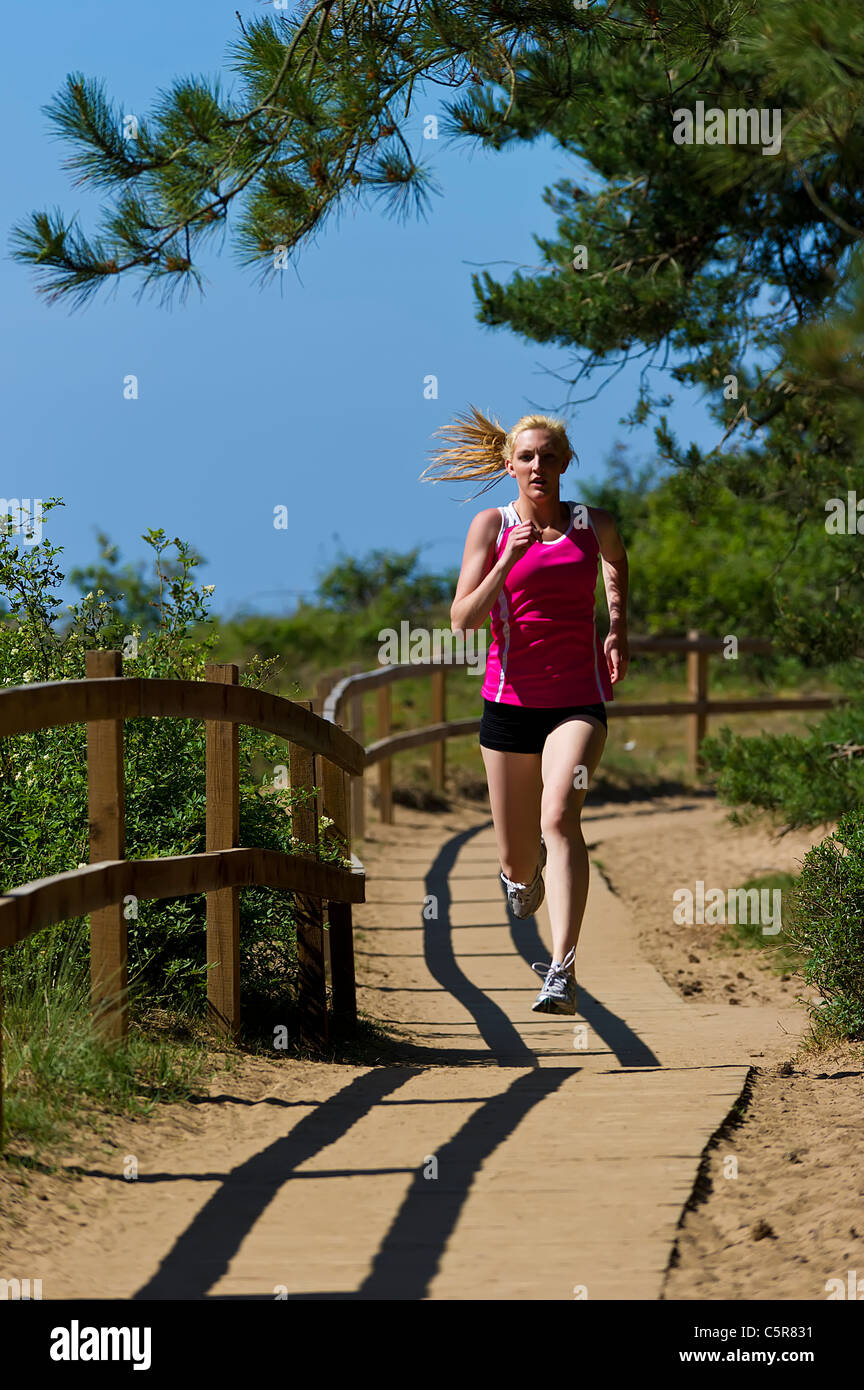 A jogger running along a beachside boardwalk Stock Photo - Alamy