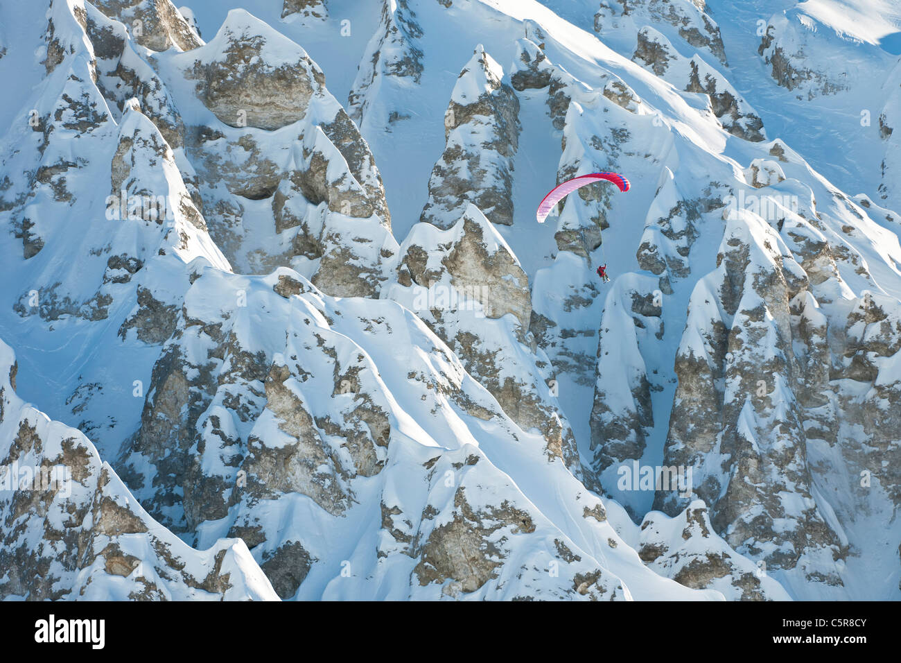 A Paraglider pilot flying past a stunning mountain rock formation Stock ...
