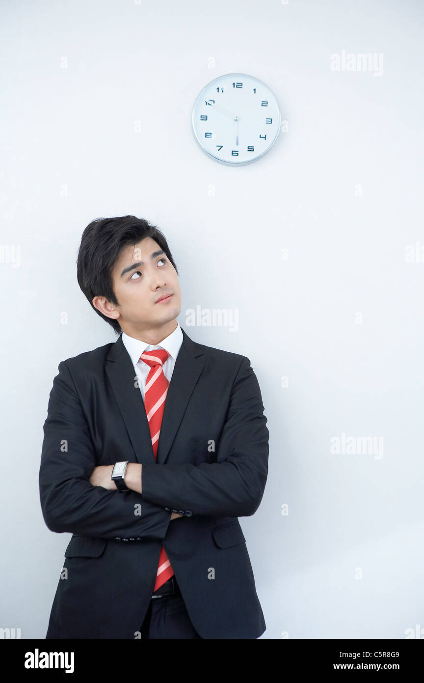 A business man below a clock on the wall Stock Photo - Alamy