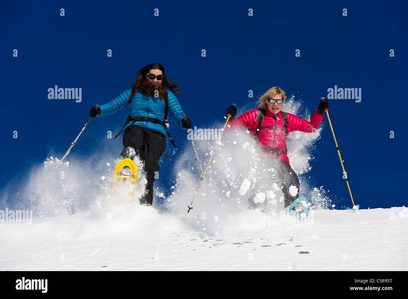 Two friends snowshoeing run through deep fresh powder snow Stock Photo ...