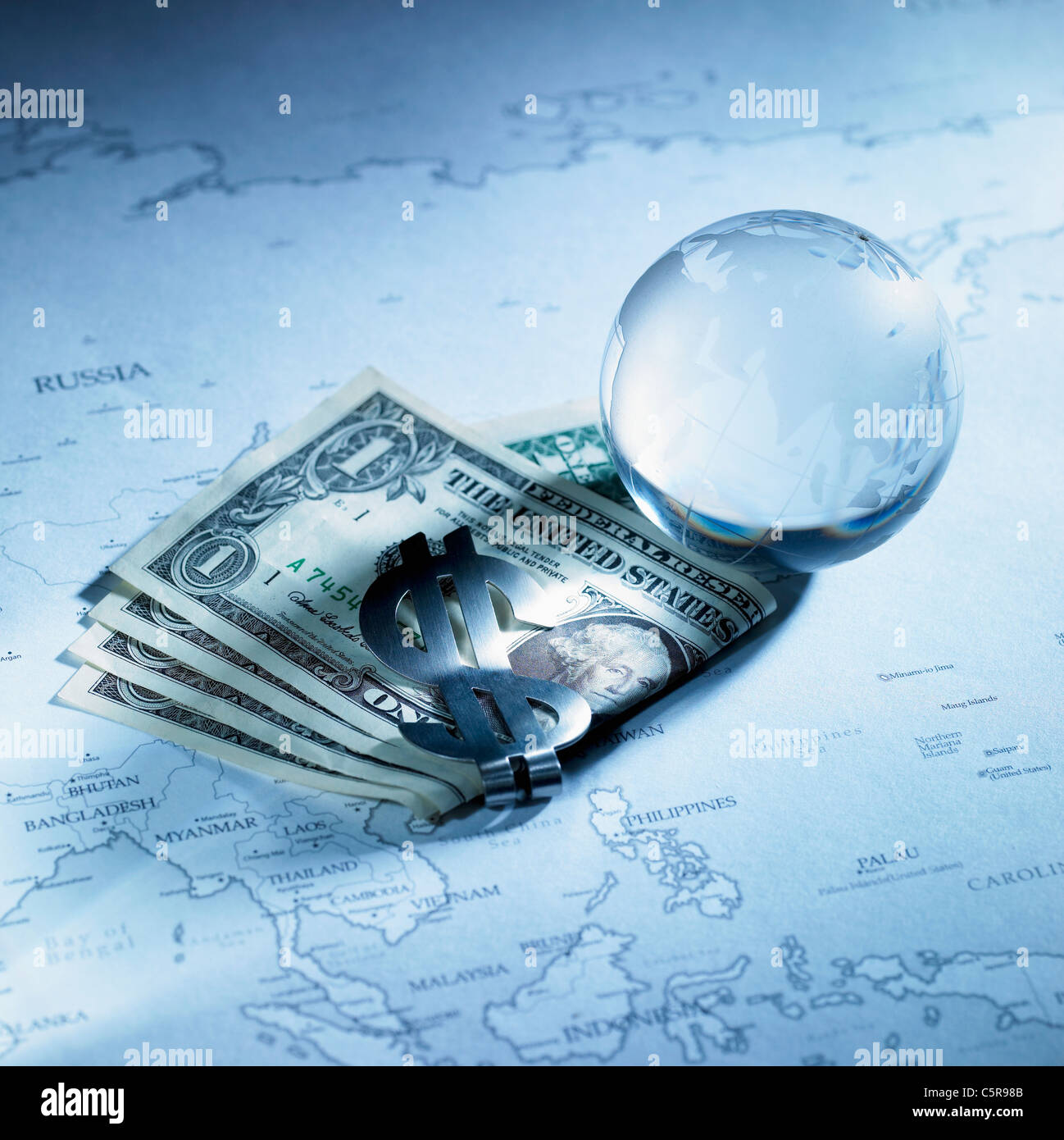 Money and a globe on a map Stock Photo - Alamy