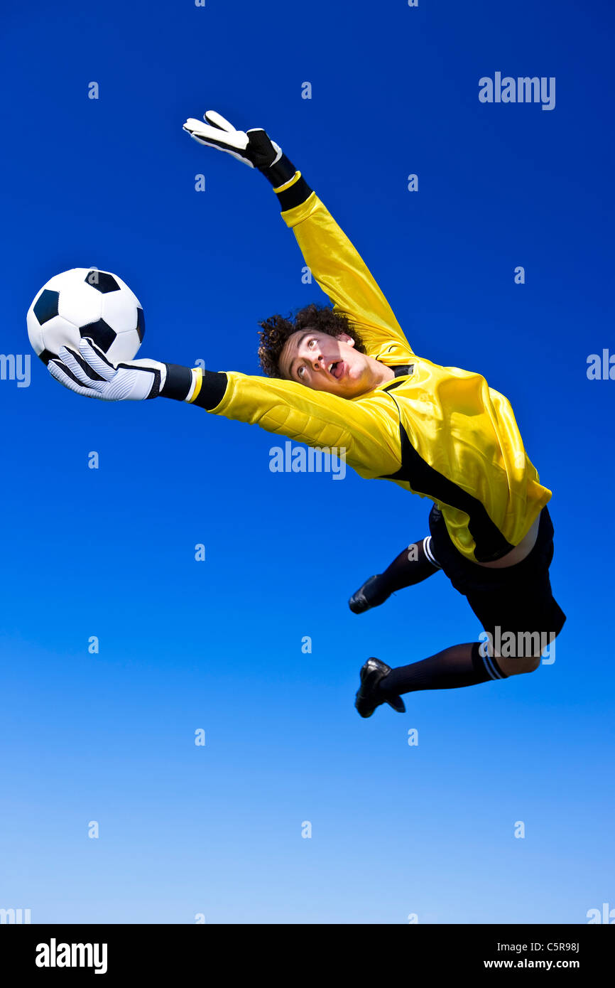 A goalkeeper gets a hand to the ball to make the save Stock Photo - Alamy