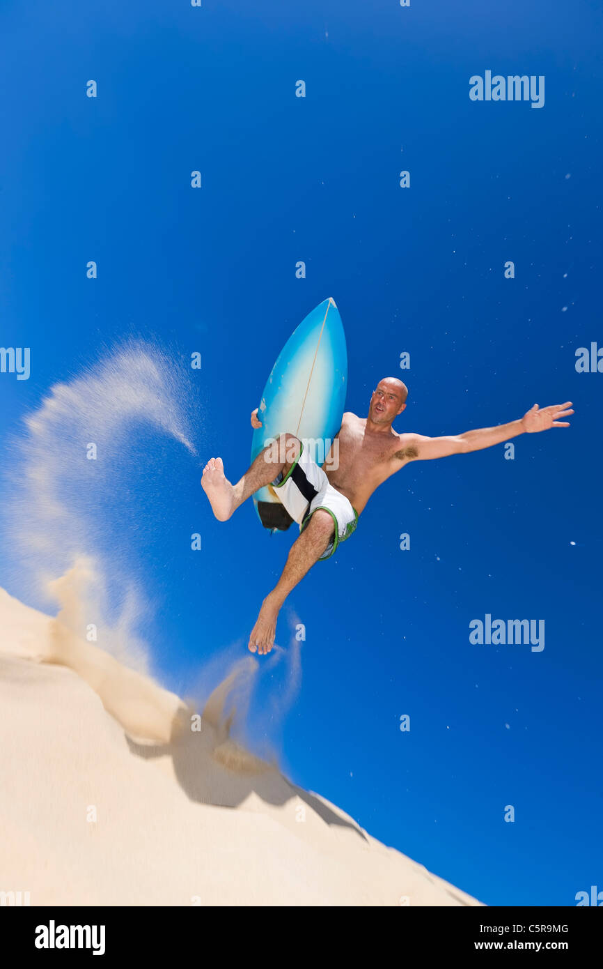 A surfer jumps of sand dune on way to Ocean Stock Photo - Alamy