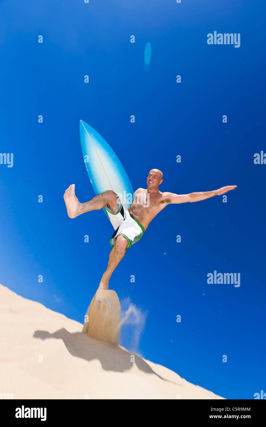 A happy surfer leaps of a sand dune at the beach Stock Photo - Alamy