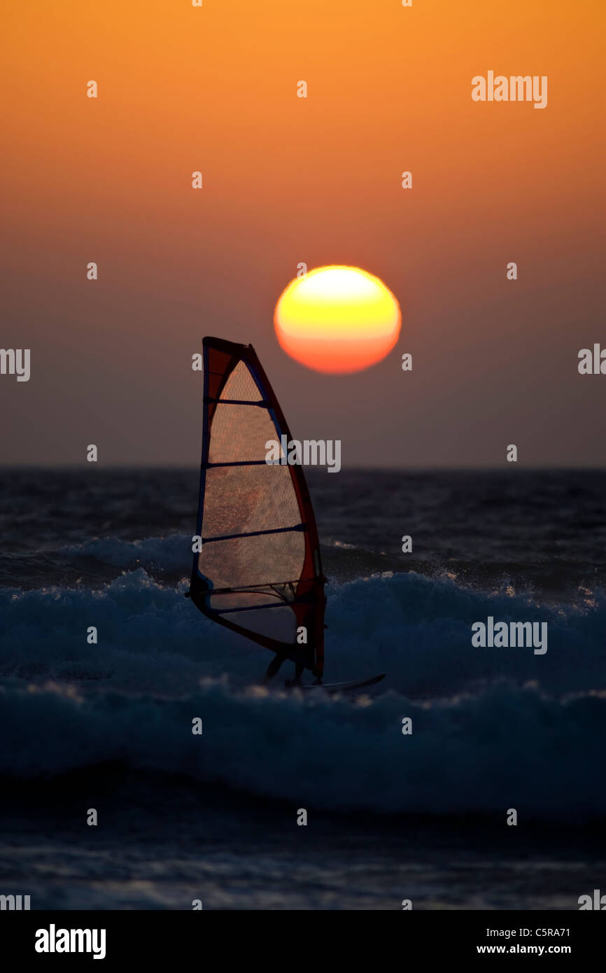 A windsurfer rides the ocean waves at sunset Stock Photo - Alamy